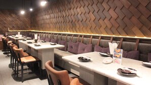 Um restaurante com um balcão comprido, várias mesas e cabines com assentos acolchoados.