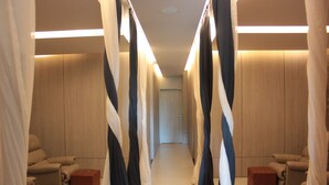 Um corredor com fileiras de áreas de estar, cada uma com uma poltrona estofada e um pequeno apoio para os pés.