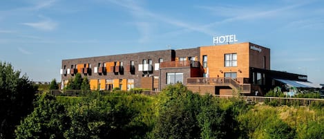 Hotel com design moderno, com vários andares e um letreiro chamativo com a palavra 'HOTEL'.