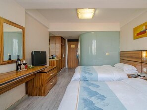 Quarto de hotel com cama, escrivaninha com televisão e espelho.