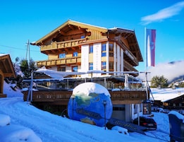Um hotel com fachada de madeira, várias varandas e um globo grande em primeiro plano.