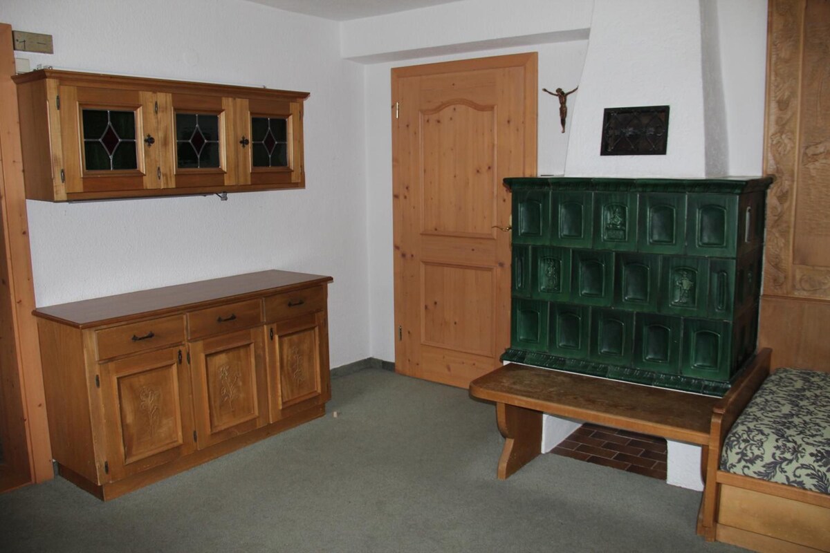 Quarto com um armário de madeira, um armário verde, uma porta de madeira e uma cama com cobertura estampada.