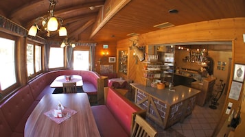 Um interior acolhedor em madeira, com área de bar, assentos e um adorno de cabeça de veado.