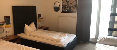 Quarto de hotel com duas camas, um espelho grande e uma janela com cortinas.