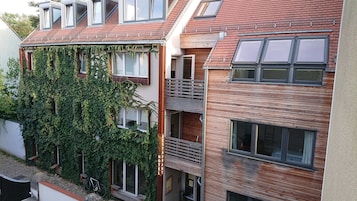 Um edifício de vários andares com um restaurante no andar térreo, com grandes janelas e uma varanda.