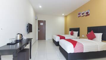 Quarto de hotel com duas camas, uma secretária com chaleira e televisão.