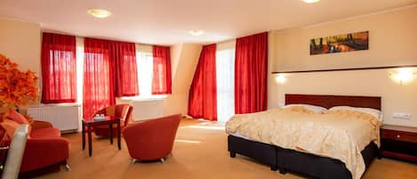 Quarto de hotel com cama, escrivaninha, cadeira e radiador.
