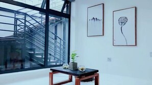 Quarto moderno com uma janela grande, uma escada e duas obras de arte emolduradas na parede.