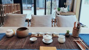 Uma área de refeições com mesa posta para uma refeição, com tigelas, pratos e uma cesta de vime.