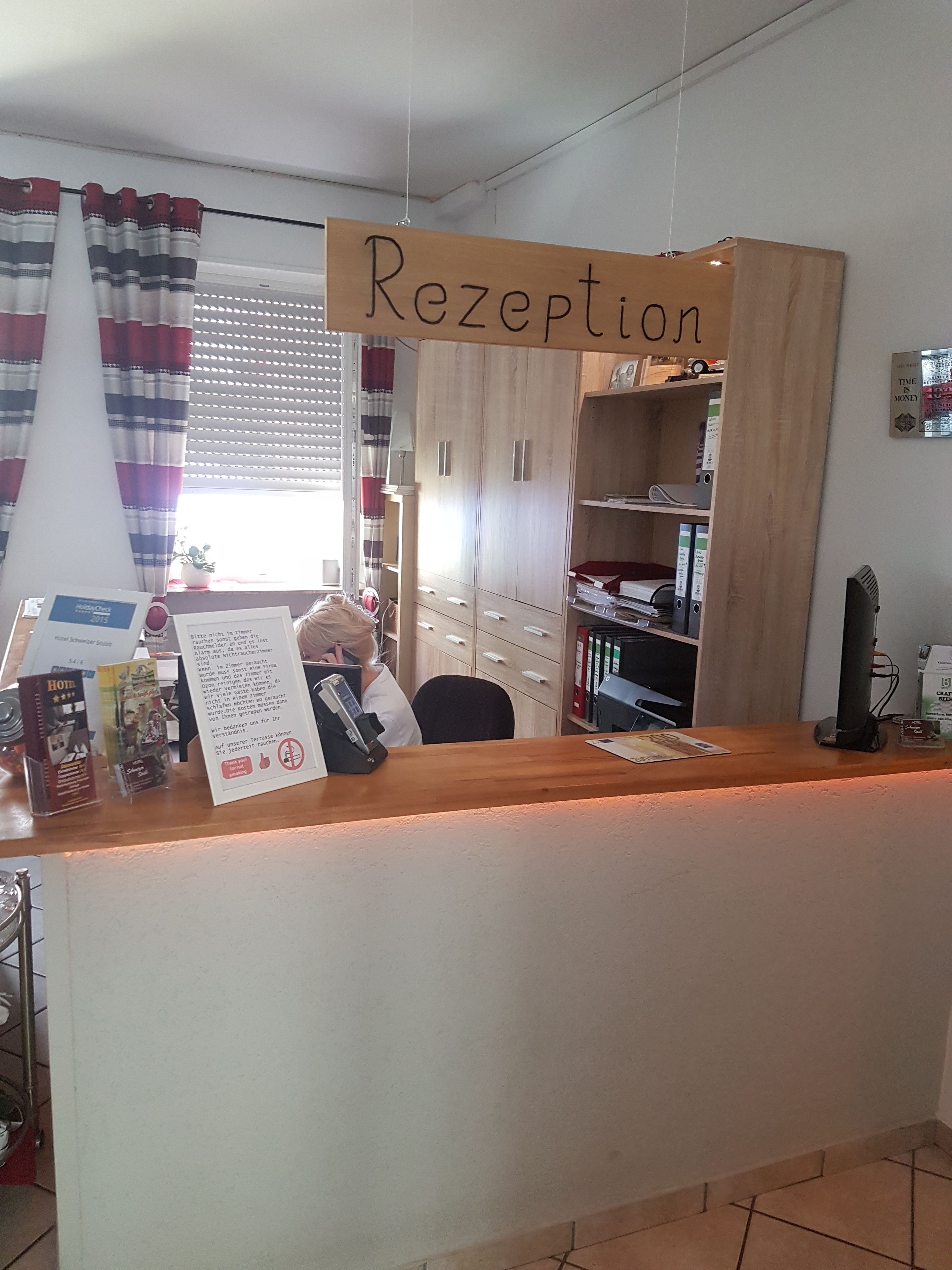 Uma receção com uma placa a dizer 'Rezeption' no hall de um hotel.