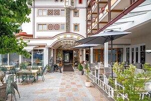 Um hotel com chão quadriculado, área externa para sentar e entrada decorativa.
