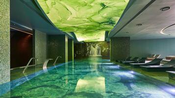 Piscina interior moderna com teto verde e espreguiçadeiras ao longo da borda.