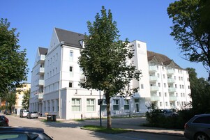 Um hotel de vários andares com fachada plana, varandas e céu claro.