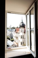 Uma janela com vista para um edifício com cúpula e torre.