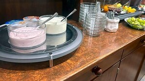Balcão de buffet com diversos alimentos e utensílios.