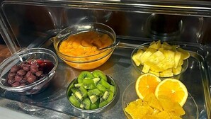 Um buffet com tigelas de cerejas, mangas, kiwis, abacaxi e fatias de laranja.