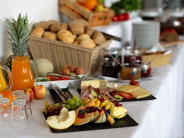 Buffet de café da manhã com diversas frutas, queijos e pães.