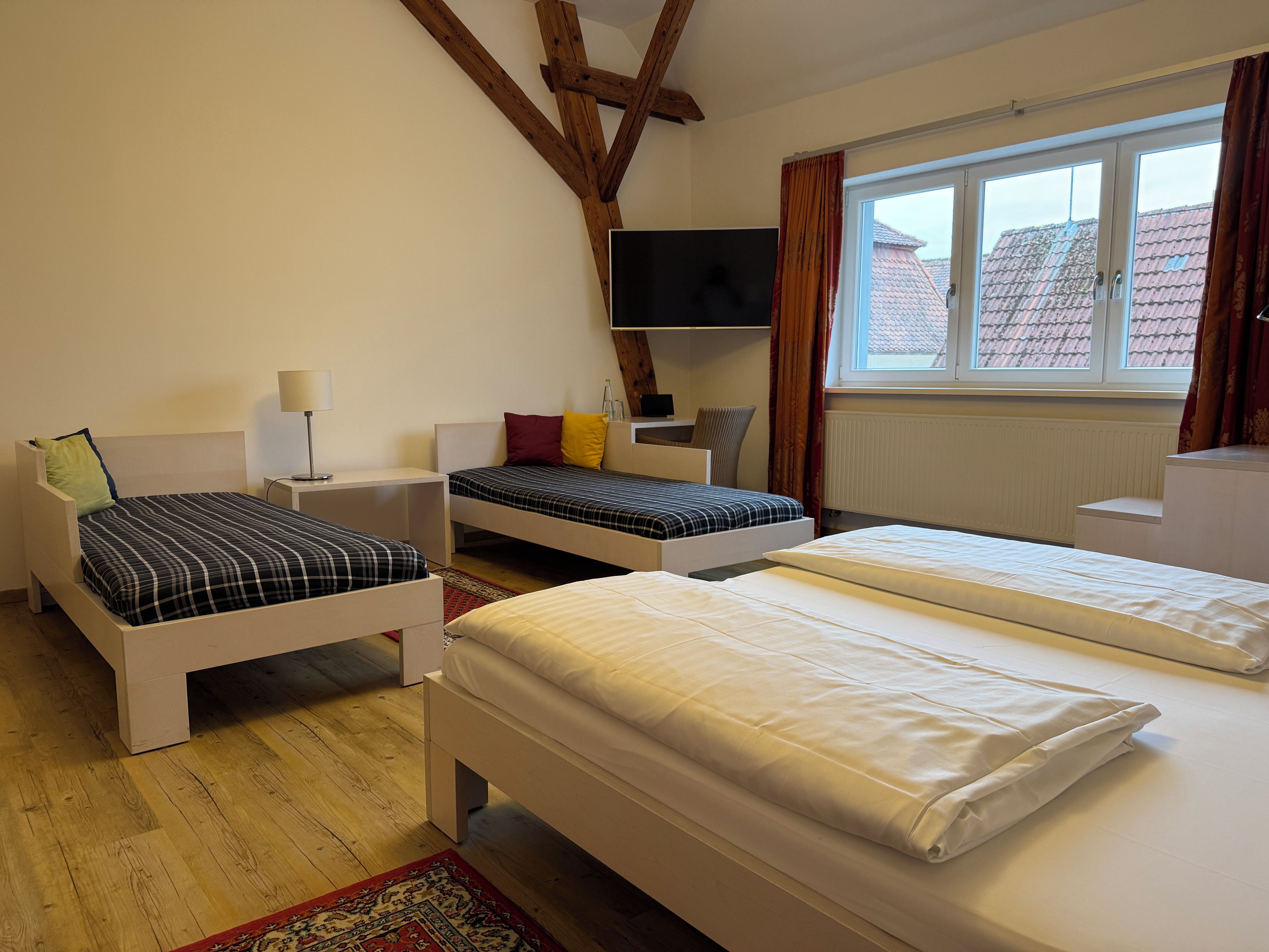 Quarto com duas camas, televisão e janela com cortinas.