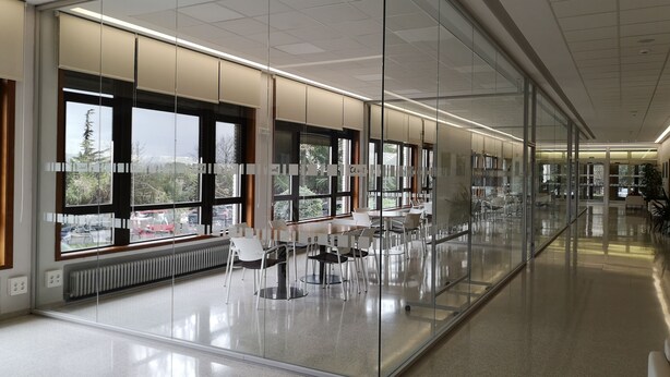 Uma biblioteca moderna com paredes de vidro, janelas amplas e um layout limpo e organizado.