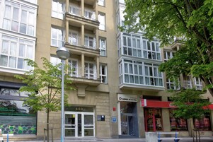 Um edifício com vários andares, entrada no andar térreo, janelas amplas e varandas.