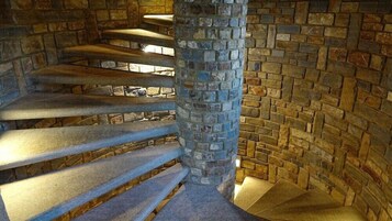 Uma escadaria em espiral com paredes de pedra e degraus de madeira.