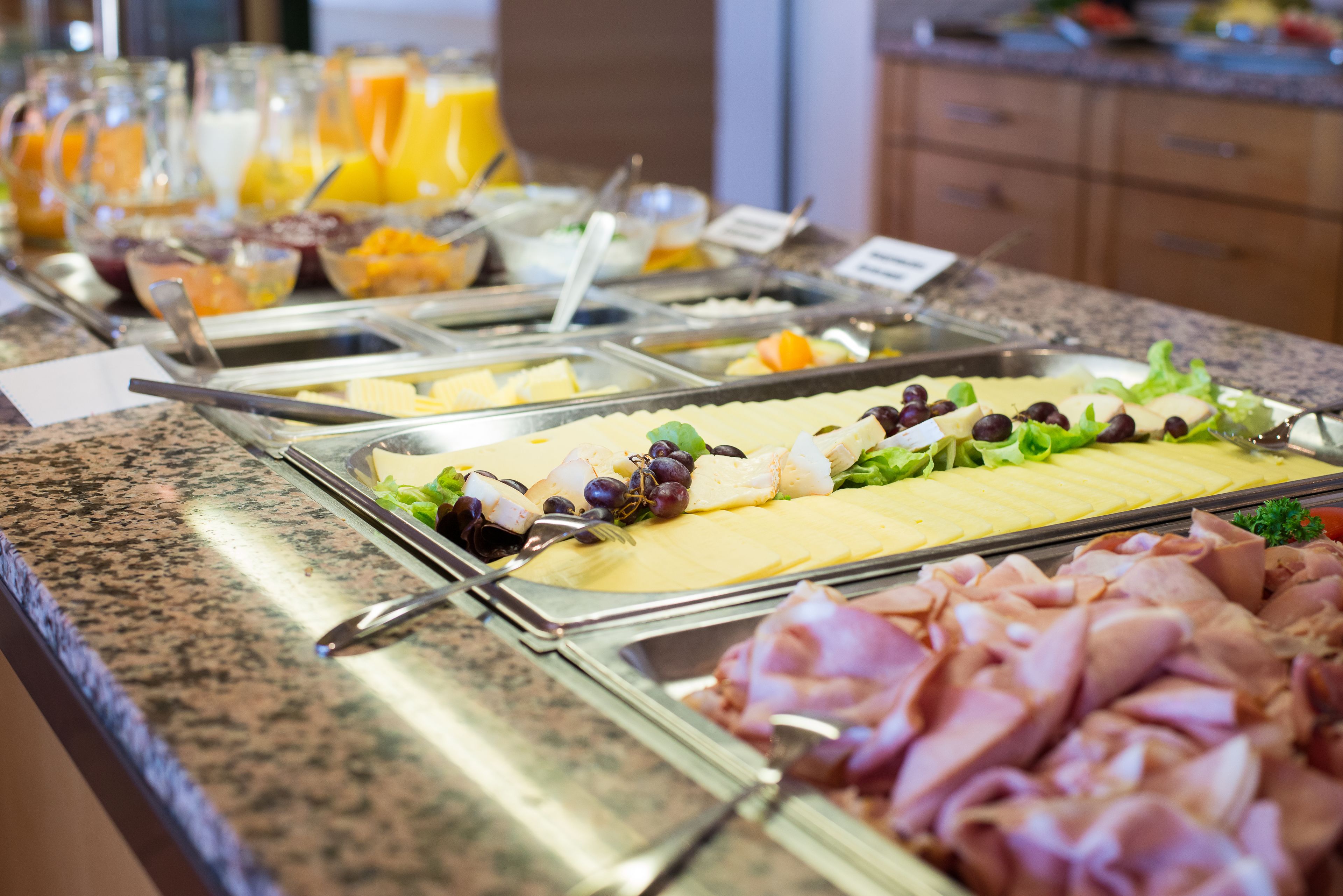 Buffet com diversas opções de comida, incluindo carnes, queijos e frutas.