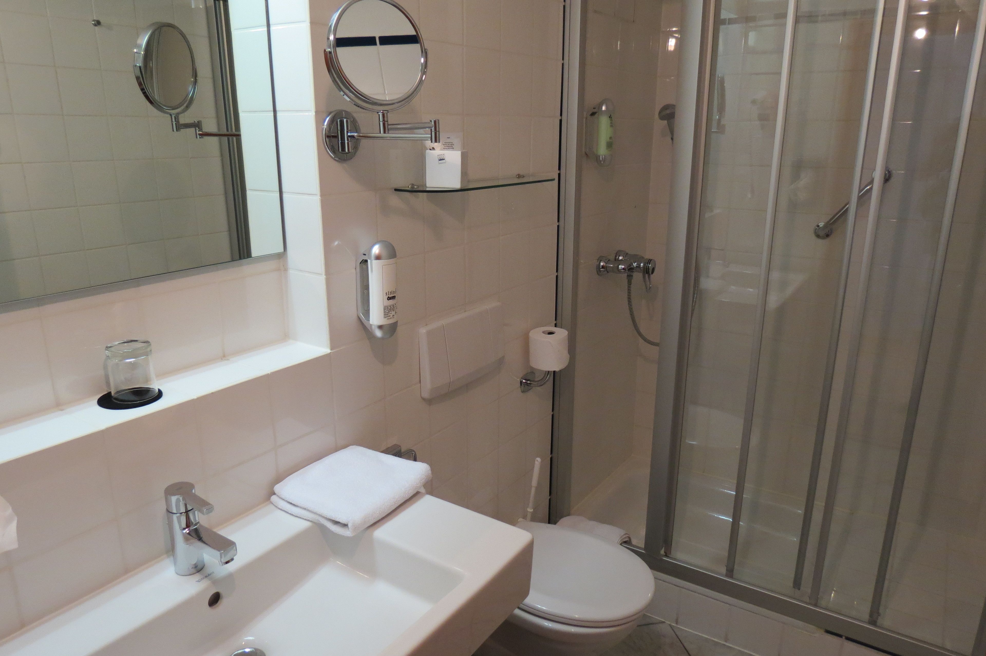 Uma casa de banho moderna com cabine de duche em vidro, lavatório branco e sanita.