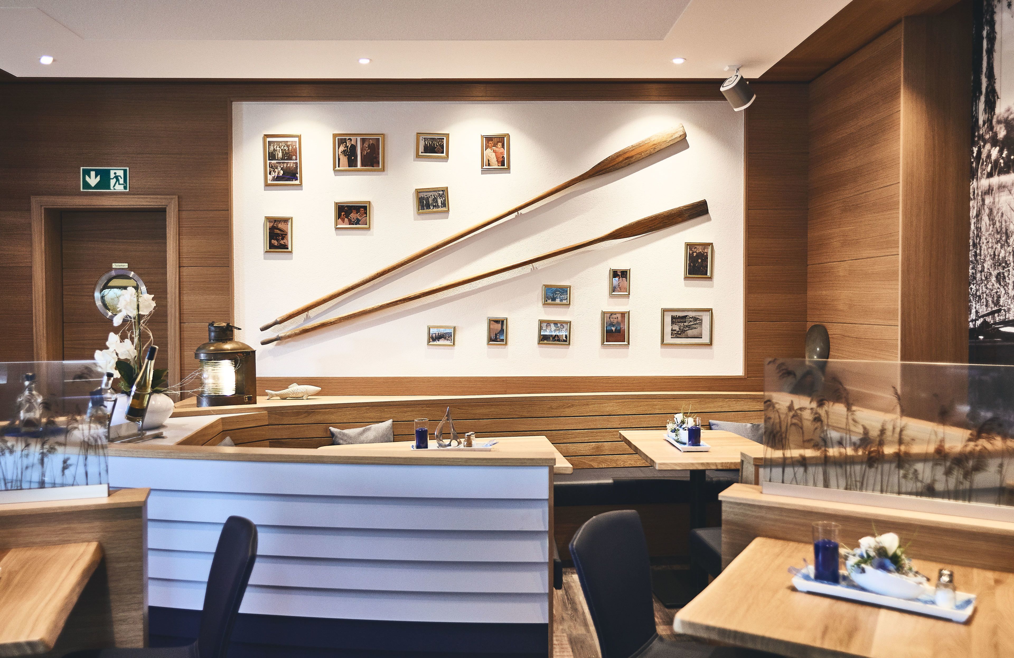 Interior de restaurante com painéis de madeira, uma longa viga de madeira na parede e quadros emoldurados.