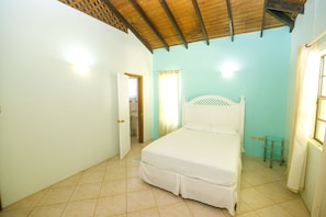 Quarto com cama, porta, janela e chão em azulejos.