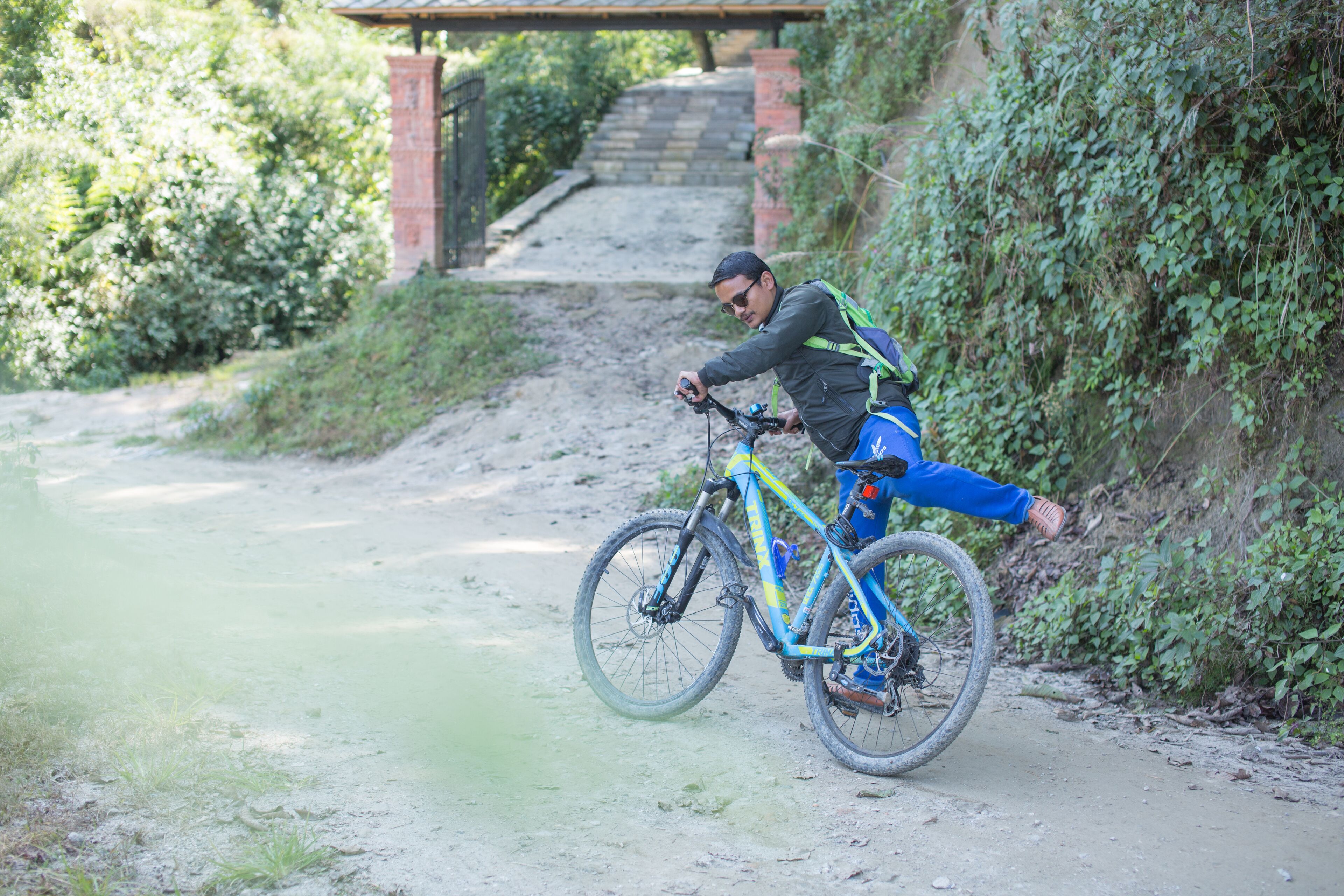 Uma pessoa andando de bicicleta de montanha por uma trilha de terra, com vegetação em ambos os lados.