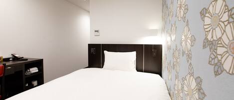 Quarto de hotel com cama, secretária e guarda-roupa.