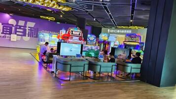 Um salão de jogos indoor com máquinas de jogos, áreas de estar e um letreiro de neon.