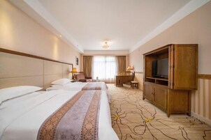Quarto de hotel com duas camas, televisão, escrivaninha e guarda-roupa.