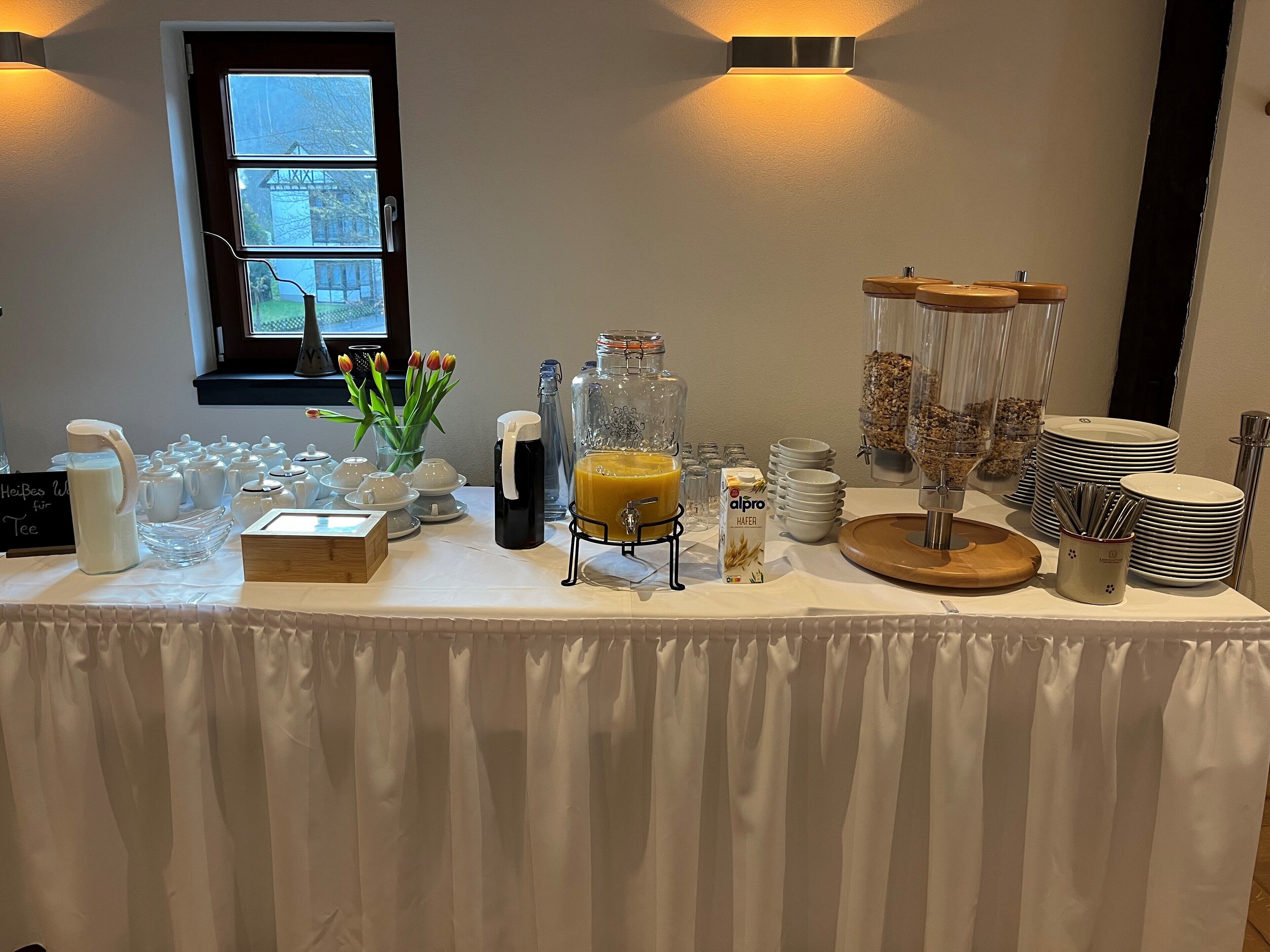 Disposição de buffet de café da manhã com diversos alimentos e utensílios.