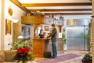 Um saguão de hotel com balcão de recepção, um sofá e um elevador.