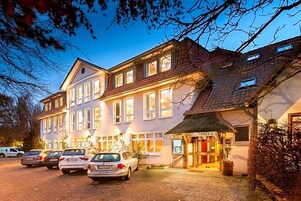 Um hotel de vários andares com arquitetura europeia tradicional, apresentando uma entrada central com uma loja no andar térreo.