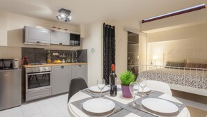 Quarto de hotel compacto com cozinha compacta, área de refeições com mesa redonda para dois e cama com colcha estampada.