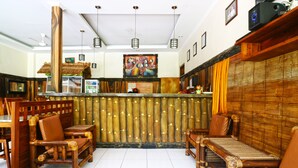 Interior de restaurante com mobiliário de madeira, um painel de bambu e um balcão.