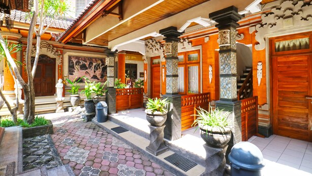 Um pátio tradicional com piso de azulejos, portas de madeira e plantas em vasos.