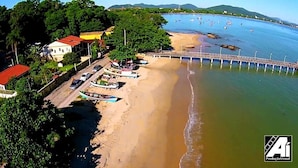 Uma área costeira com praia, barcos e uma ponte.
