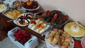 Buffet com diversos alimentos, incluindo bolos, doces e frutas.