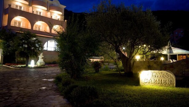 Um hotel com fachada de pedra, janelas em arco e entrada bem iluminada.