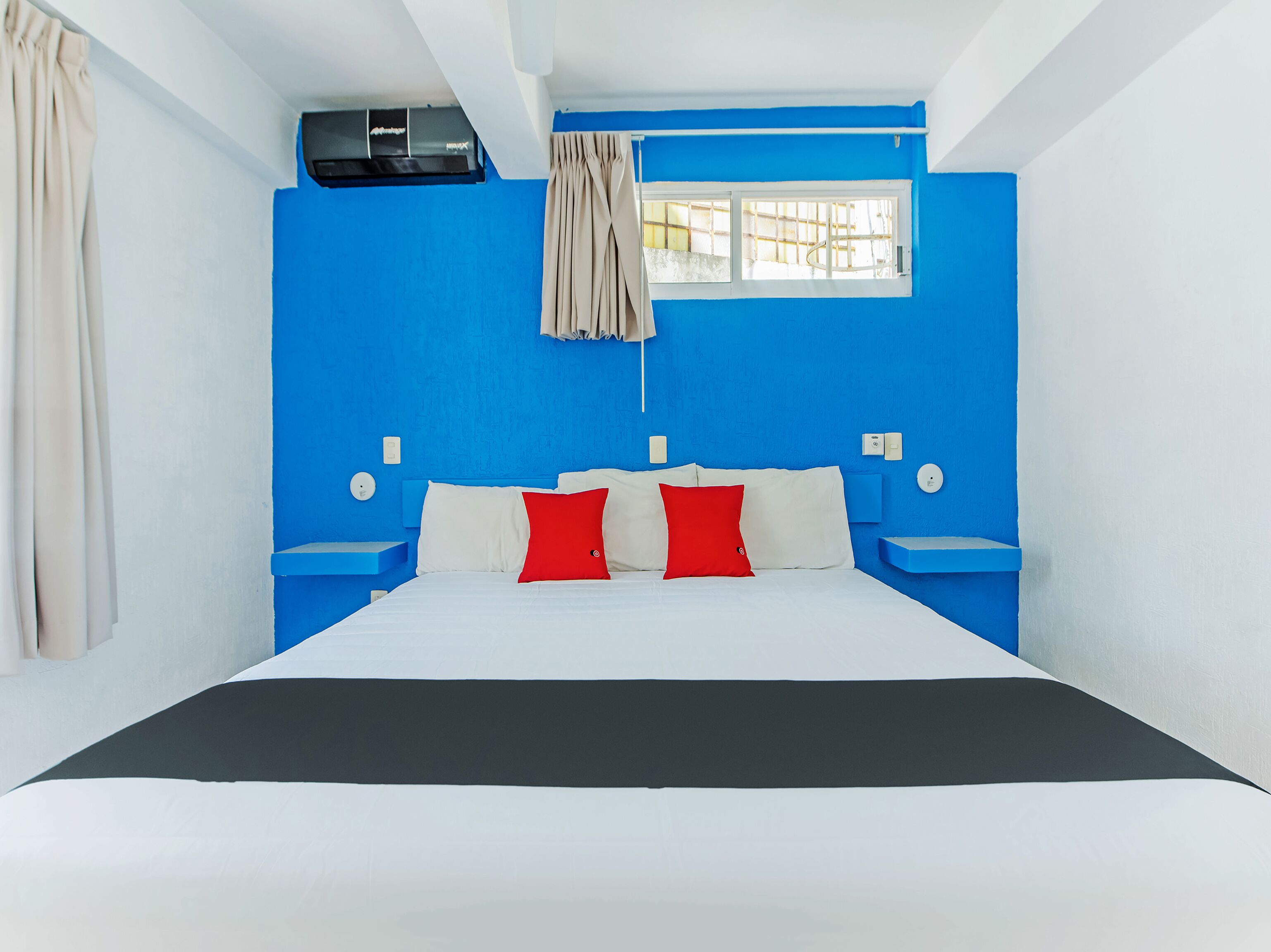 Quarto com cama, janela, cortinas e aquecedor na parede.