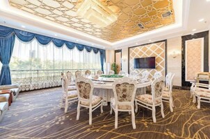 Uma sala de jantar de hotel com uma mesa redonda, cadeiras e uma televisão.