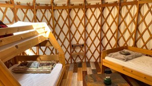 Um quarto aconchegante com beliches, uma mesinha pequena e piso de madeira.