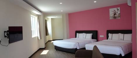 Quarto de hotel com duas camas, televisão, uma mesinha e uma cadeira.