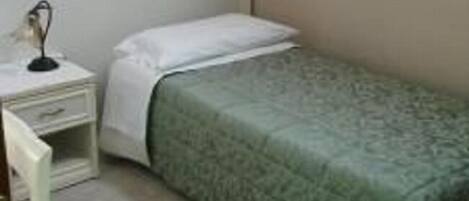 Quarto pequeno e bem organizado, com uma cama de solteiro, mesa de cabeceira e um quadro pendurado na parede.