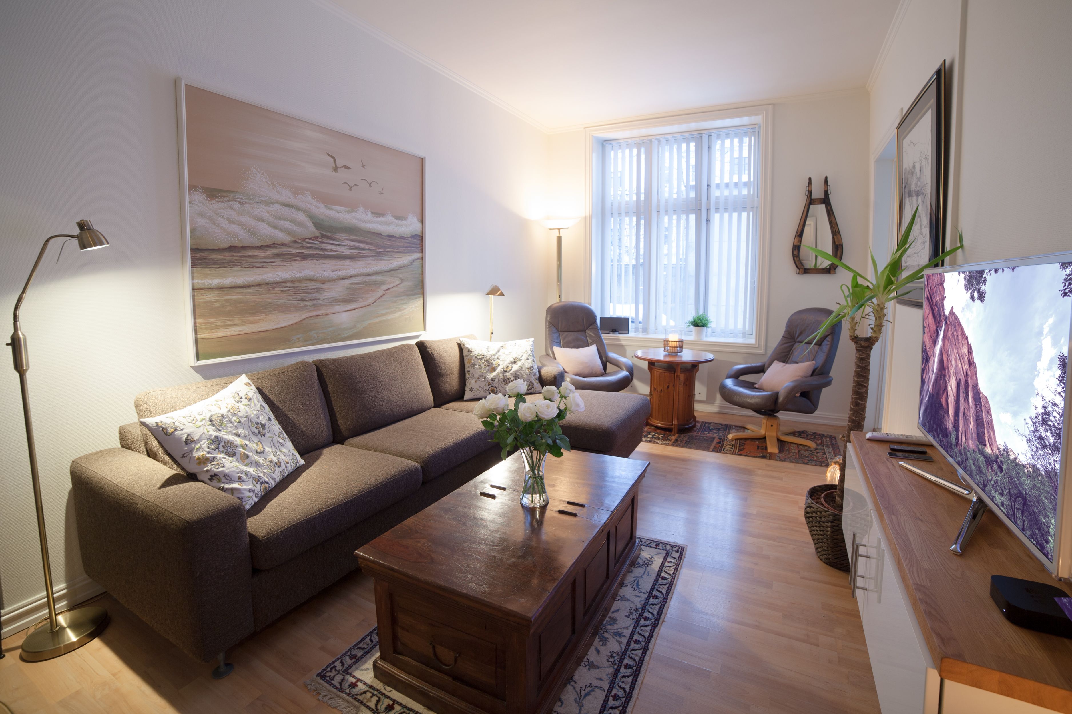Sala de estar com sofá, mesa de centro e pintura de ondas.