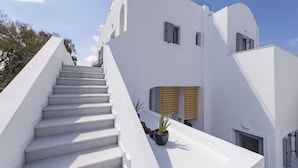 Um edifício branco com uma escadaria que leva a uma porta.