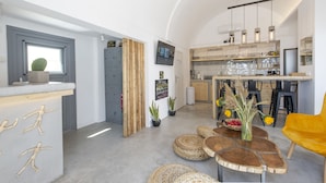 Cozinha moderna com ilha central, detalhes em madeira e área de jantar com uma cadeira amarela.